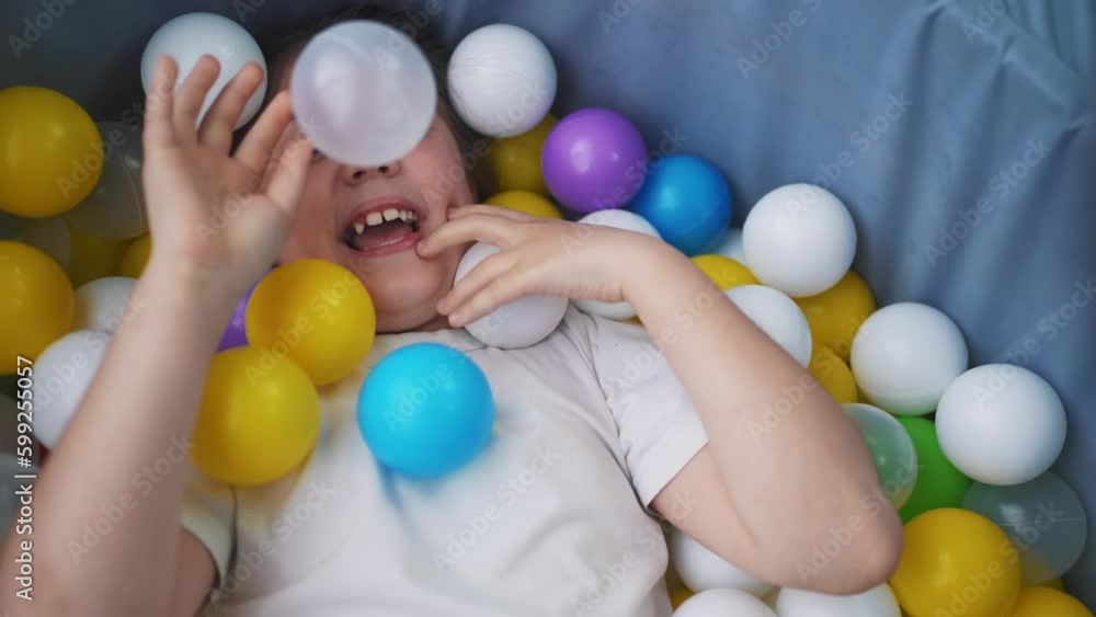 a child play in a dry pool with colored balls. happy family kid dream ...