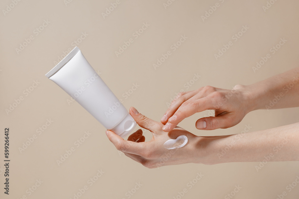 Fragile hands of a woman hold a white mockup tube of facial cream and ...