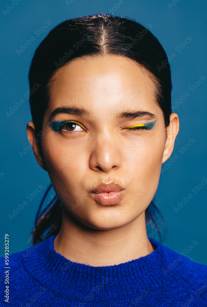 Female with bold eyeliner making a face, winking and pouting her lips ...