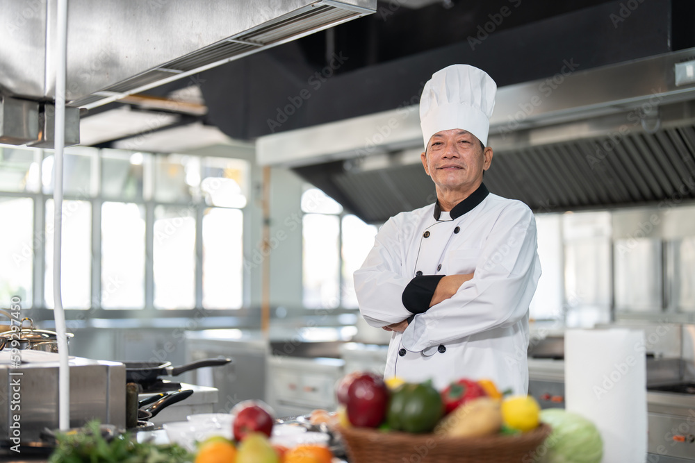 Confident senior Asian chef man in dress uniform standing and arms ...