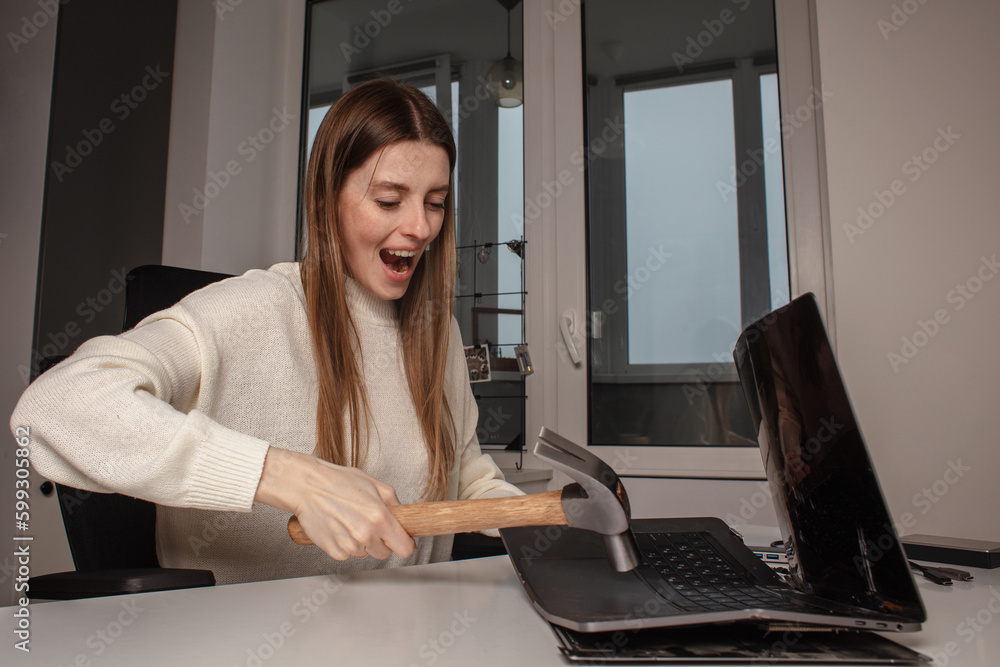 Foto de A woman with a hammer wants to break a laptop. Failure at work ...