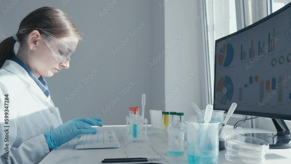 Behind a computer screen, laboratory technician enters data to study ...