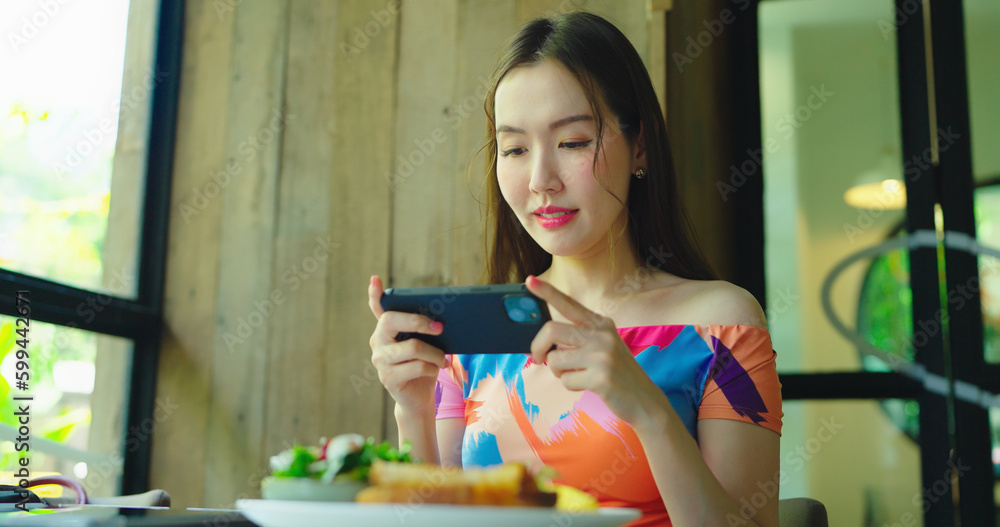 The beautiful Asian woman is using her camera to capture a photo of her ...