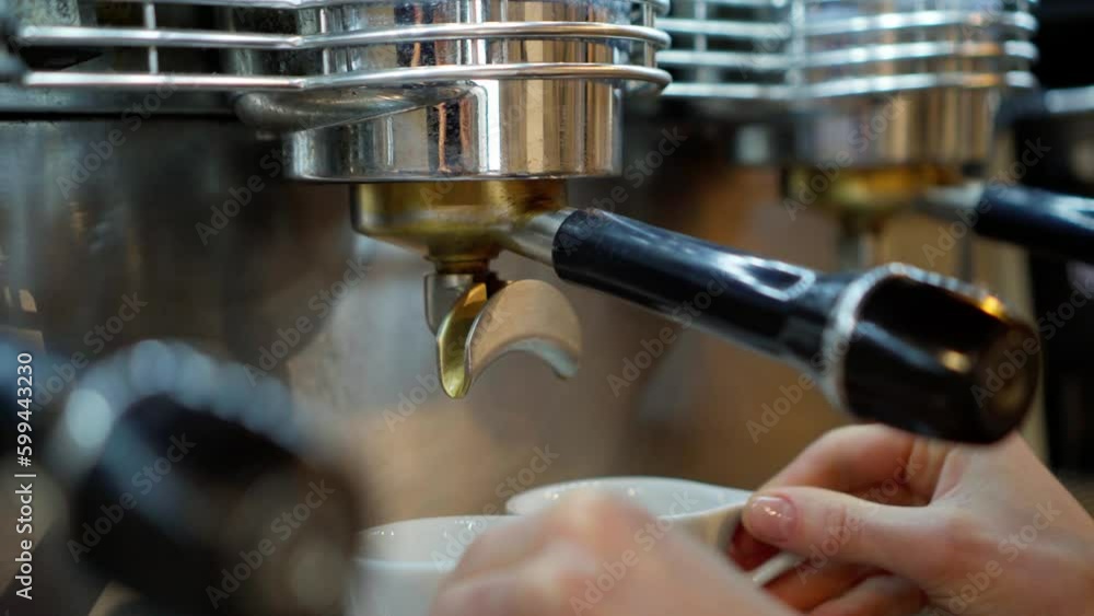 Barista hand puts on a group handle on espresso machine and puts two ...