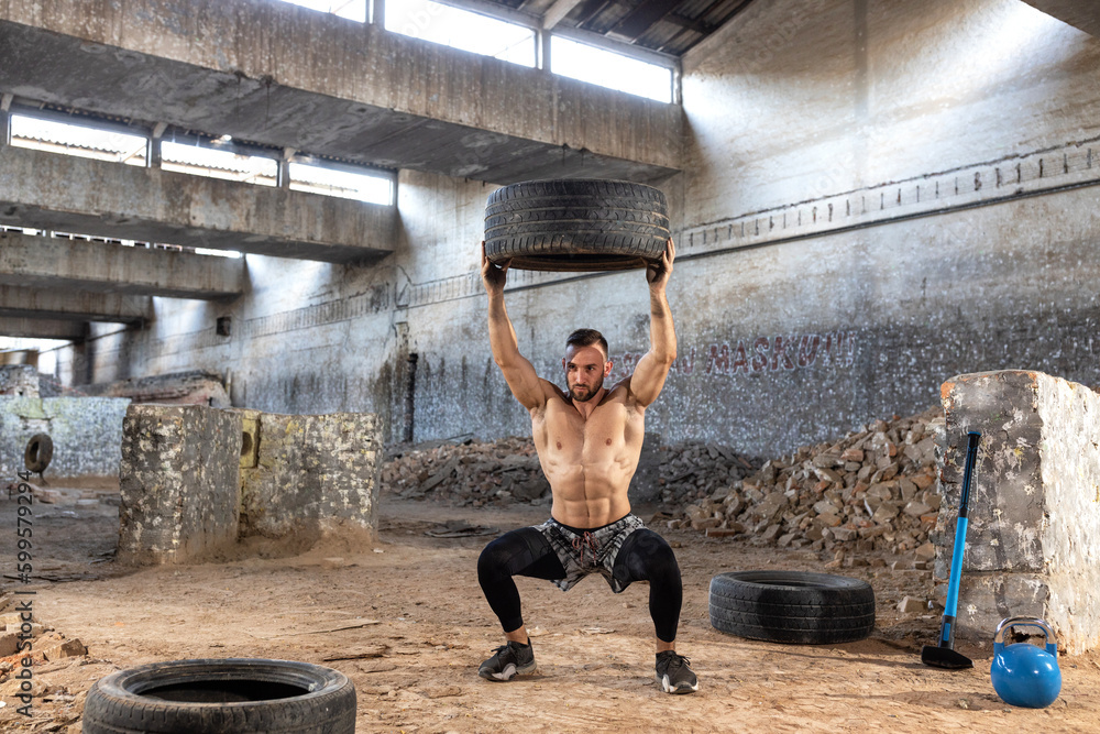 Strong ripped handsome man lifted a car tire above his head during ...