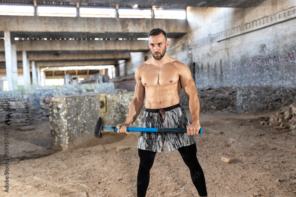 Handsome muscular young man holding a big hammer on industrial ...