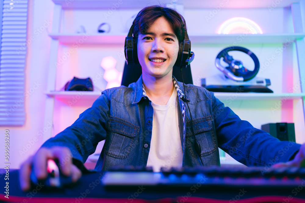 A young Asian man professional gamer wearing jeans jacket sits on a ...