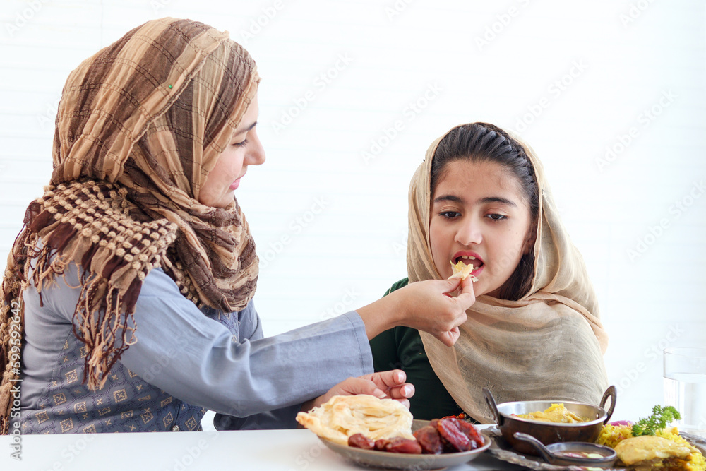 Adorable Muslim happy girl sits at kitchen table, kid with hijab enjoy ...