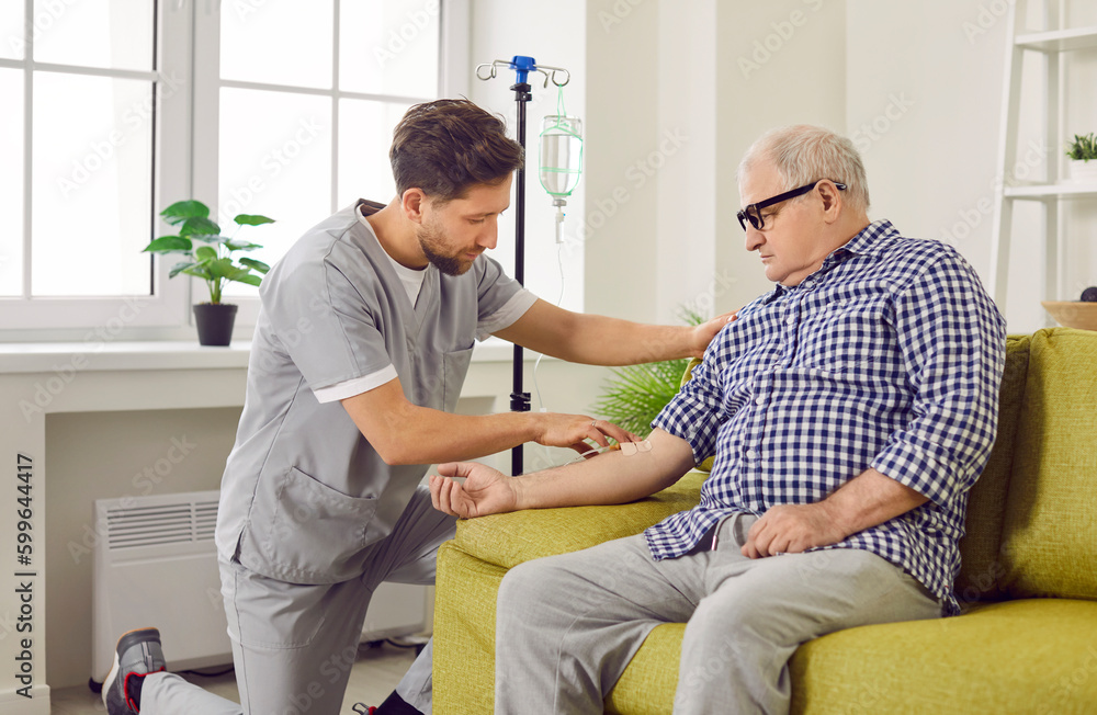 Nurse or doctor giving intravenous infusion to elderly patient. Young ...