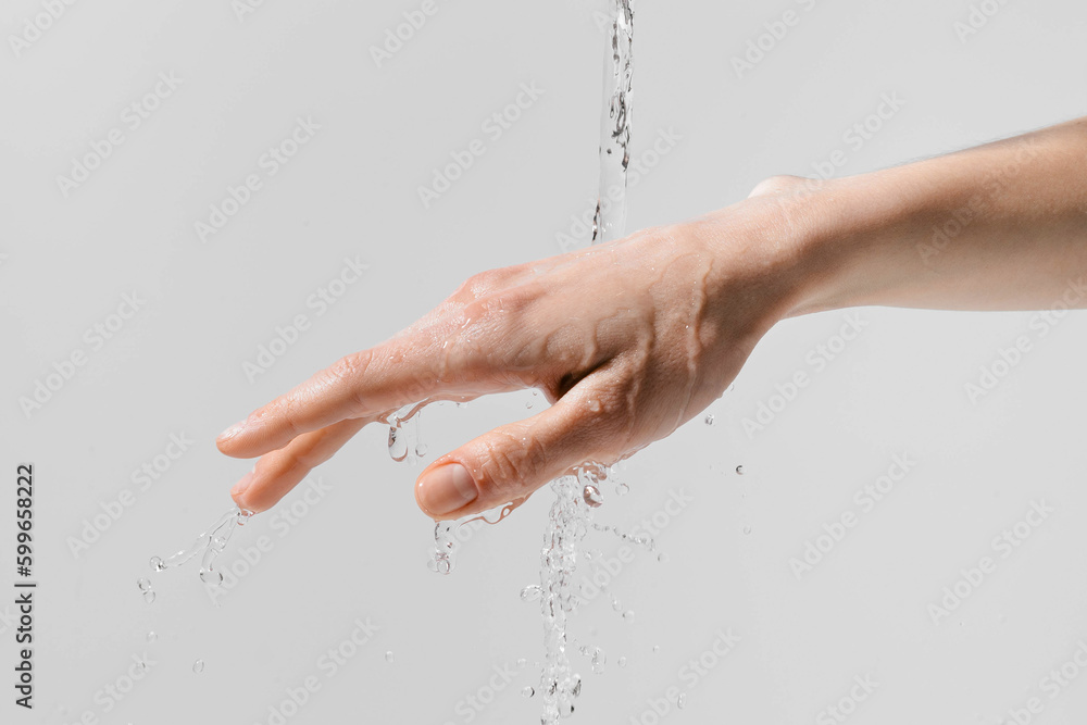 Female hand under a stream of water on a white isolated background ...