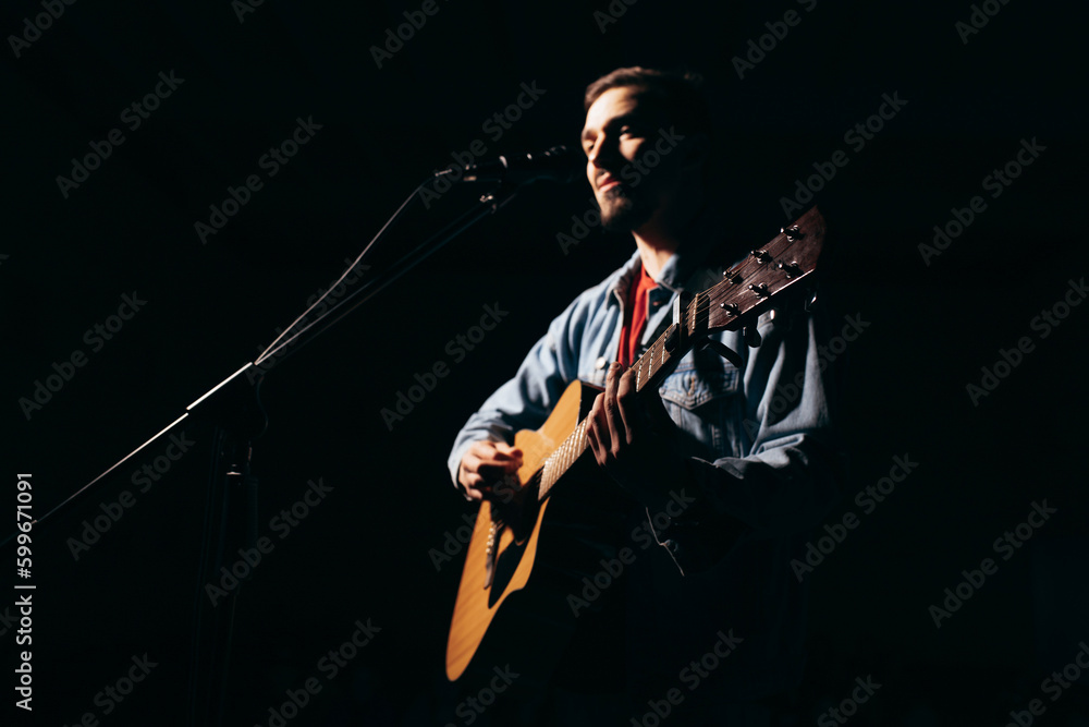 The singer plays an acoustic guitar and sings at a concert Stock Photo ...