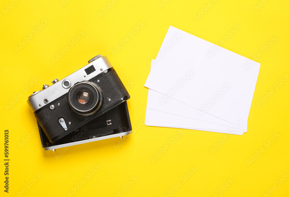 Retro camera with blank white photographs on yellow background ...