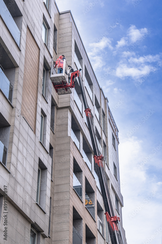 Worker cleaning the window of a building at heigt in lifting cradle ...