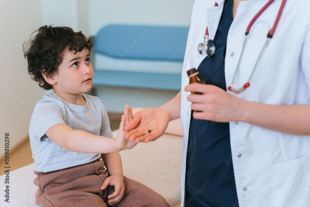 Little curly caucasian boy refusing to get pills looks at doctor at ...