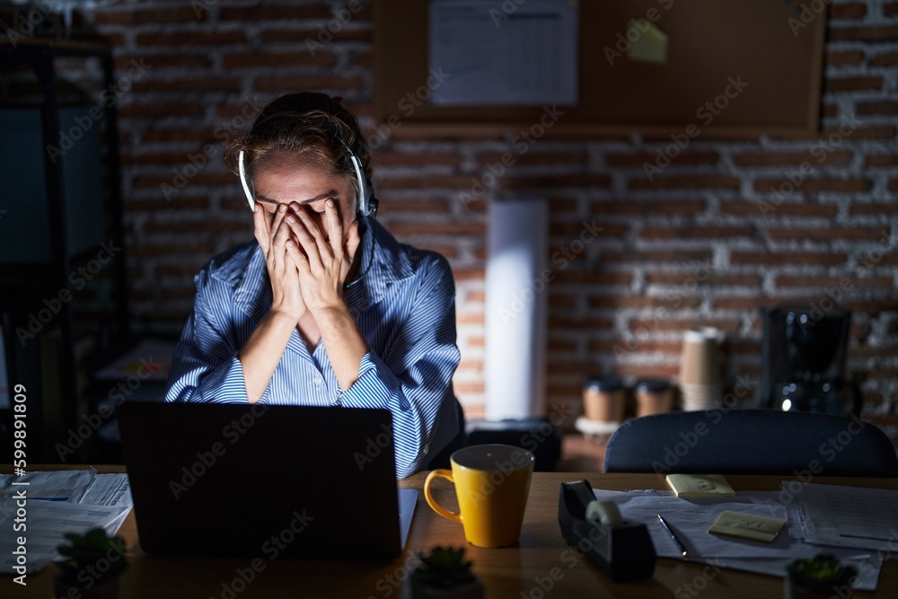 Beautiful brunette woman working at the office at night with sad ...