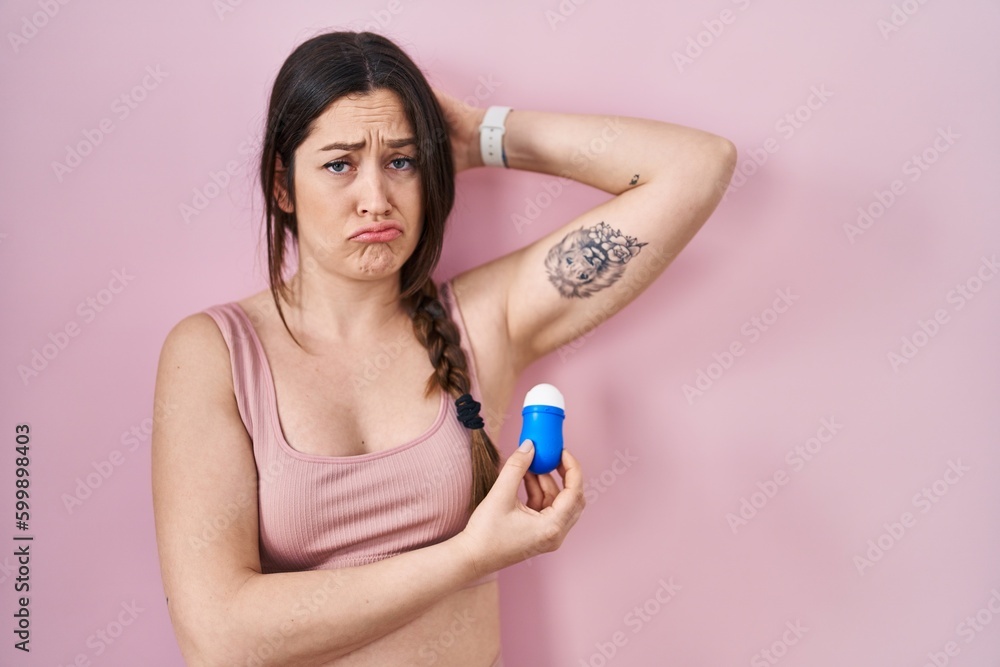 Foto de Young brunette woman using roll on deodorant depressed and worry for distress, crying ...