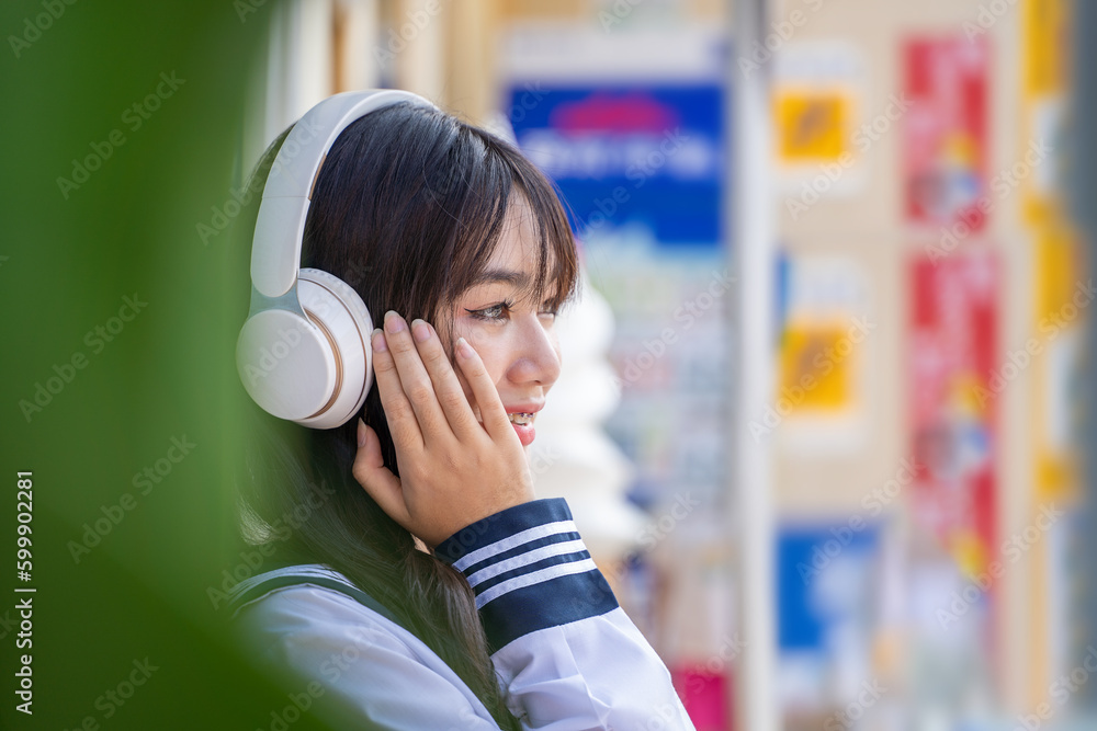 Portrait of a happy japanese school girl listening to music via ...