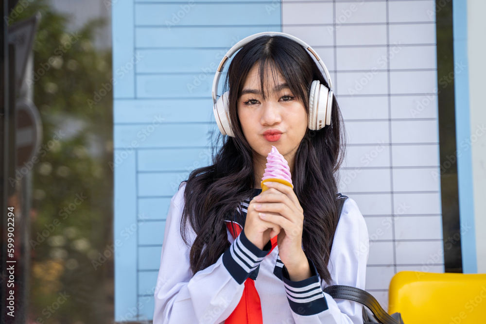 Portrait of a happy japanese school girl listening to music via ...