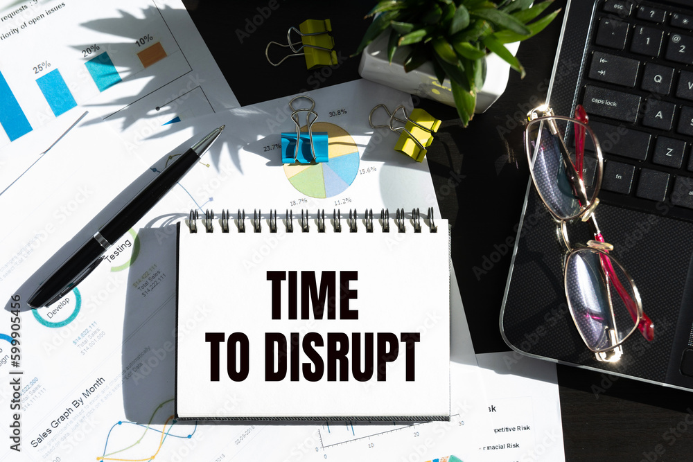 TIME TO DISRUPT text, written on a notepad with laptop, pen on the ...