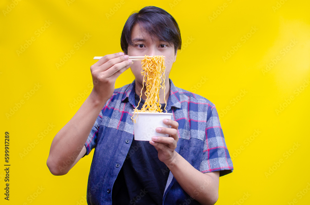 Attractive Young Asian Man Holding Noodles In The Cup Of Paper A Young Asian Man Enjoys Instan