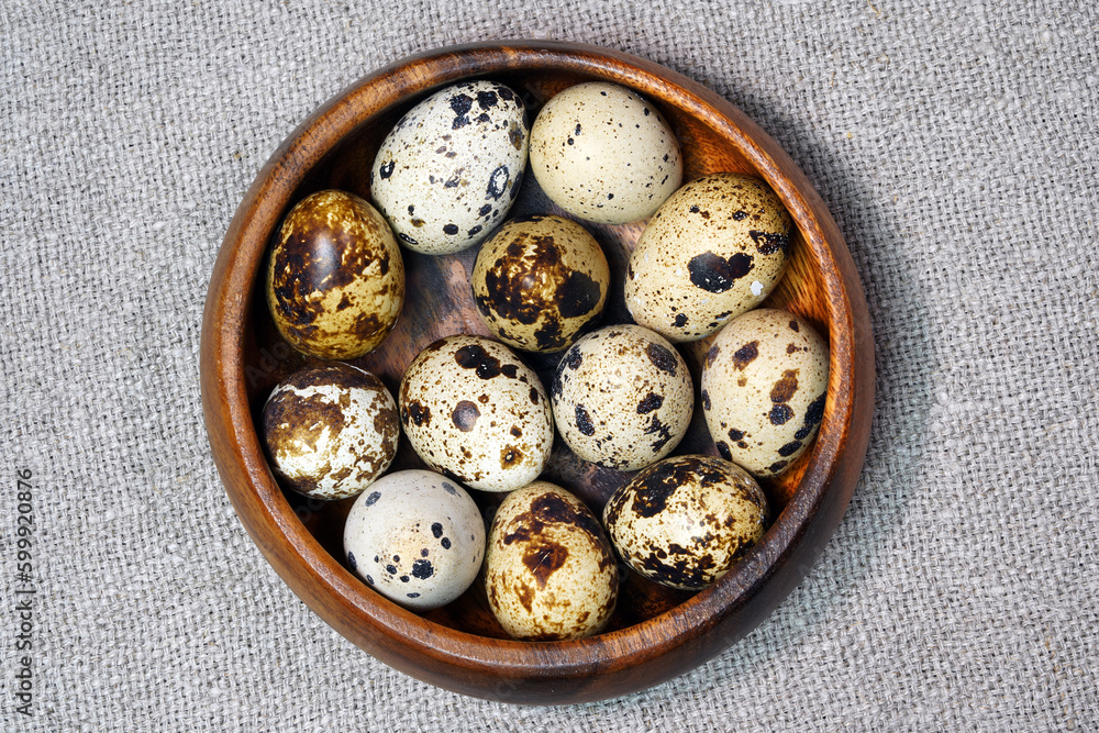 Quail eggs in a round wooden bowl on canvas, close-up, macro. Eggshell ...