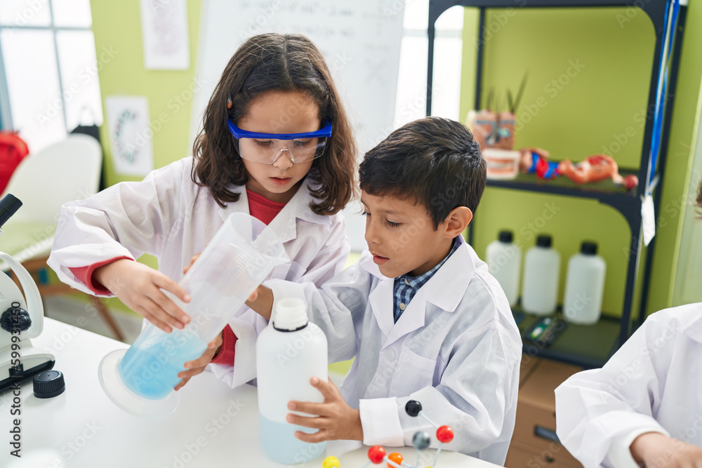 Adorable boy and girl student pouring liquid on test tube at laboratory ...
