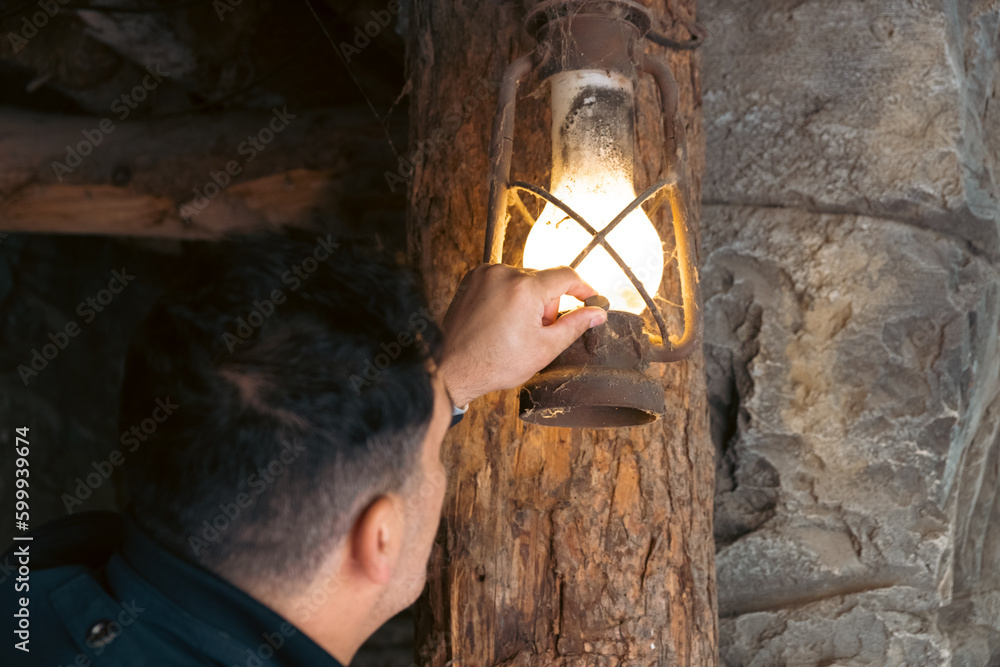 A lone figure stands in a damp, shadowy cave illuminated by the faint ...