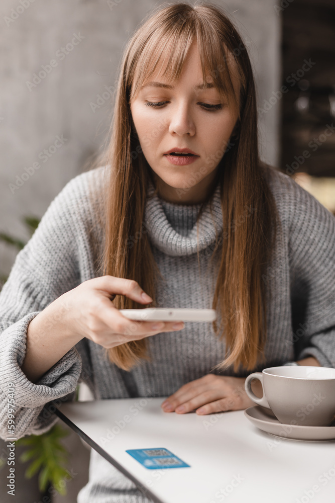 Woman scanning the barcode qr code in restaurant or cafe. Blonde woman ...