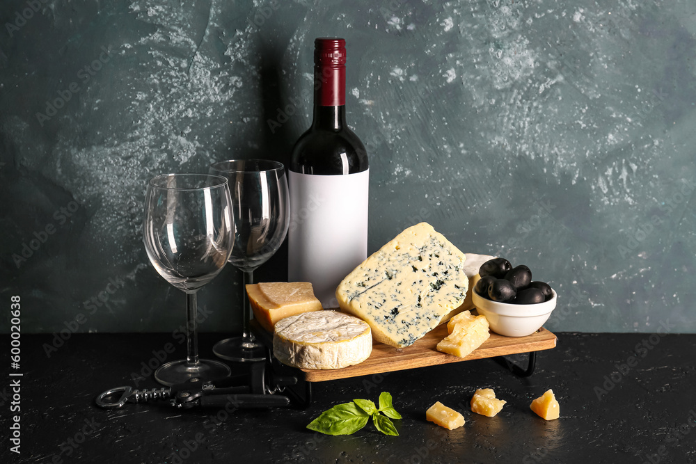 Different types of tasty cheese, glasses and bottle with wine on table ...