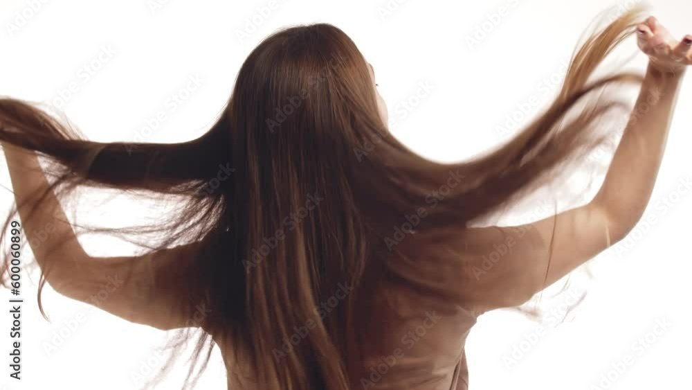 Woman slowly lifting and shaking her long shiny brown hair with both ...