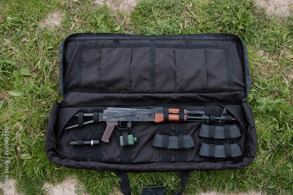 Uncovered gun case with AK-47, magazines, and flashlight lying on the ...