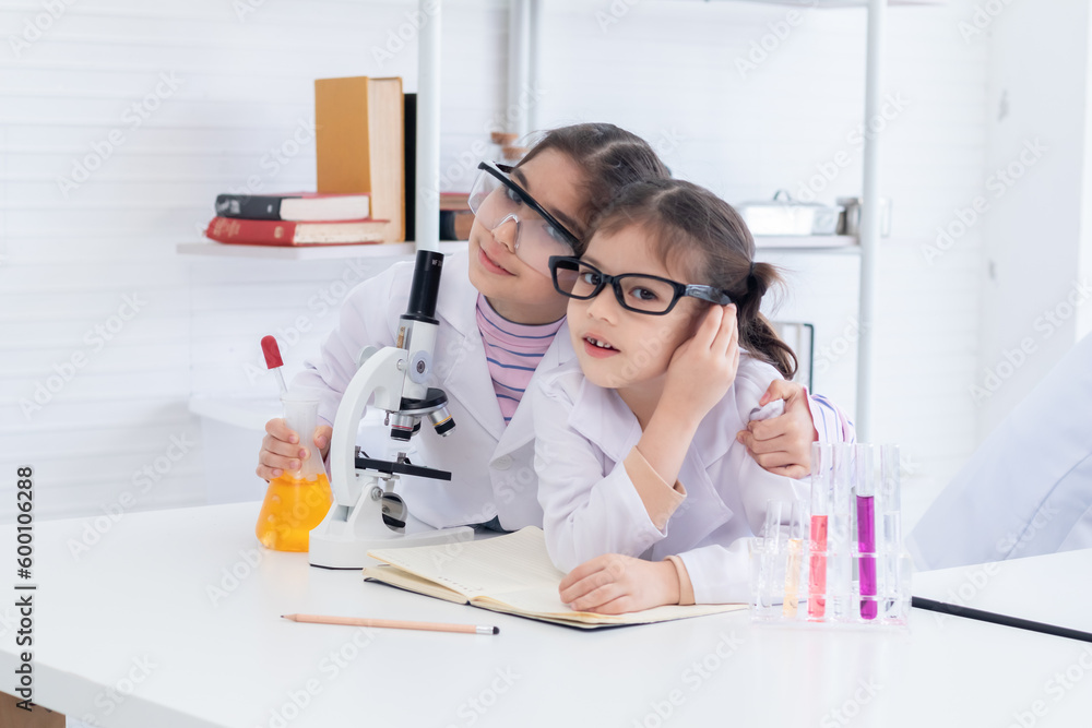 Elementary school children in white gown studying in science room, two ...