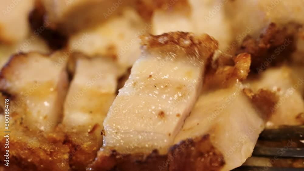 A silver fork is shown poking into a savory Chinese crispy pork dish ...