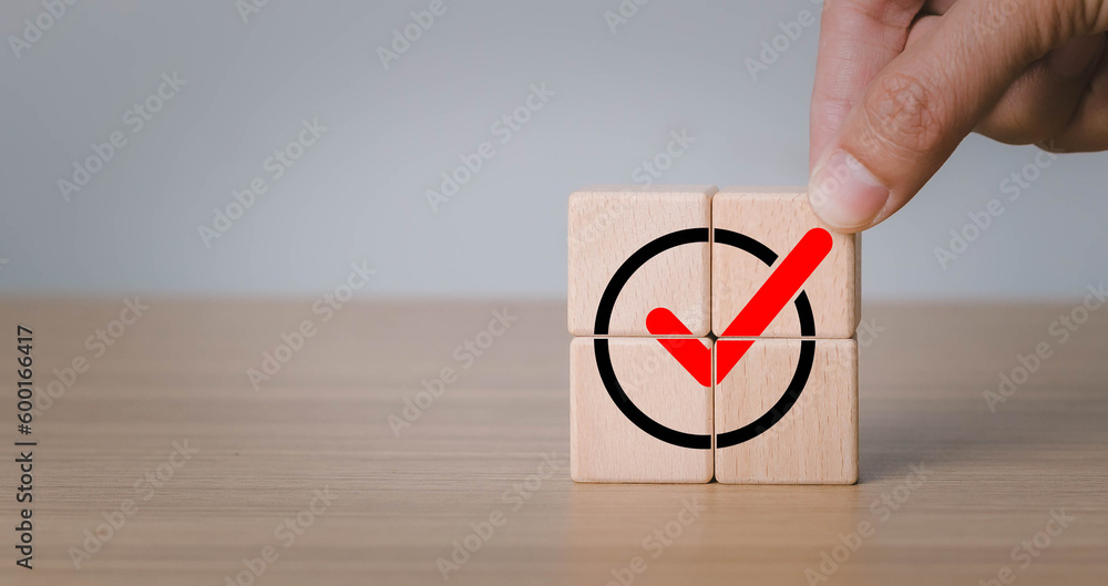 Hand placing wooden cube with green checkmark icon. Goals achievement ...