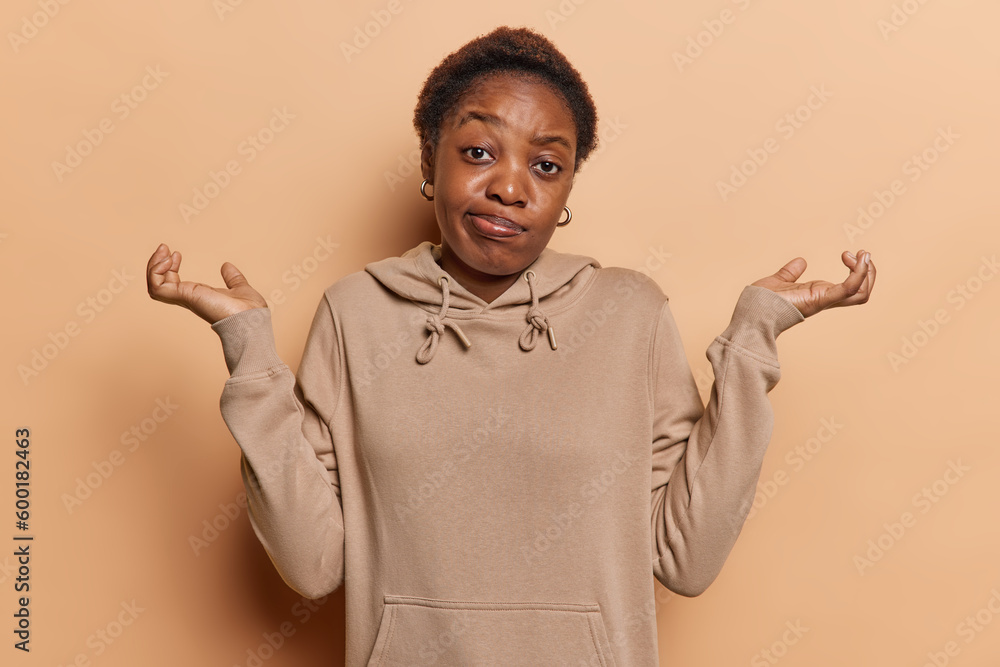 So who cares. Hesitant dark skinned woman shrugs shoulders spreads ...