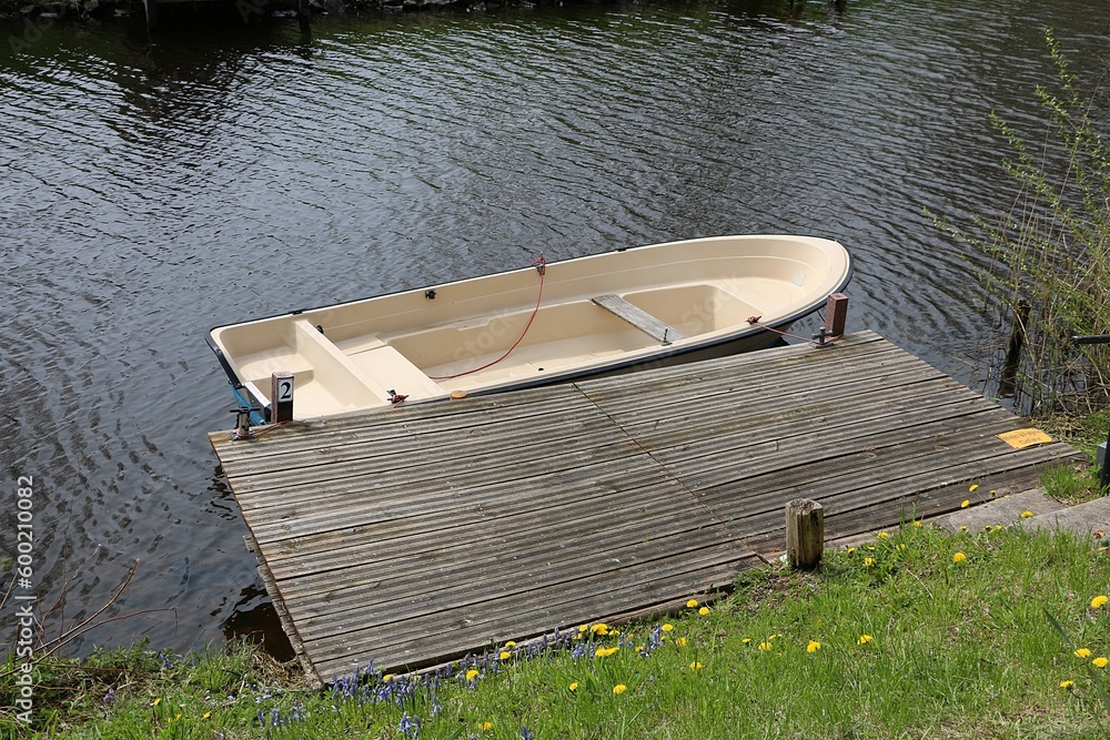 small bright empty old rowing boat is moored to the wooden pier on a ...