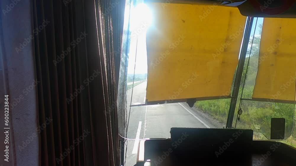 Sun shines brightly through curtain on driver's window of moving bus ...