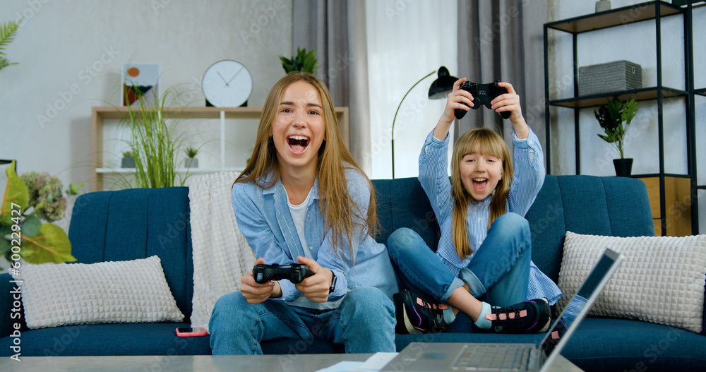 Lovely friendly cheerful two different ages girls playing video games ...