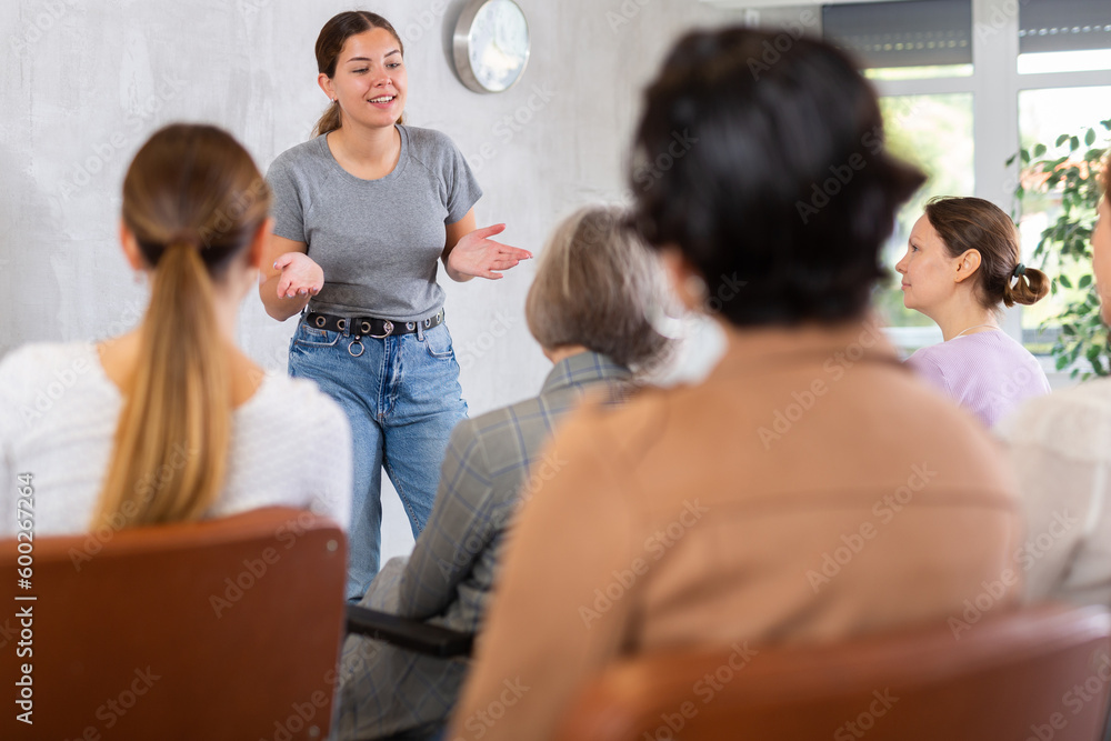Positive friendly young girl giving lecture to group of women of ...