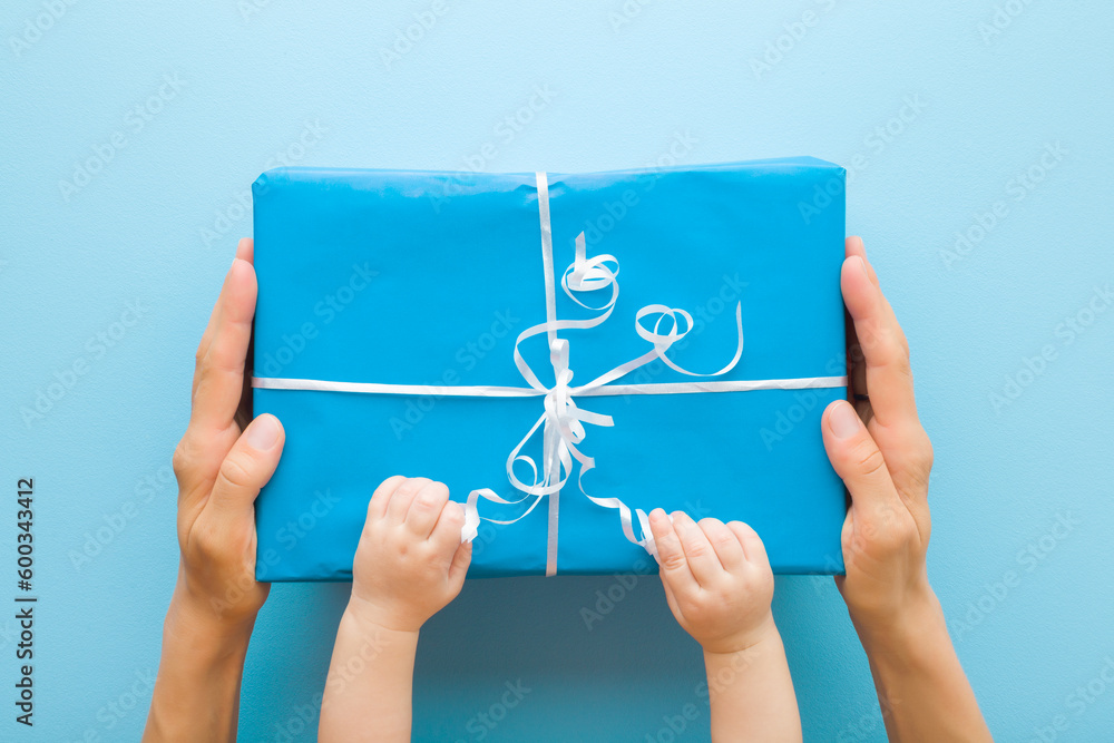 Mother hands giving big wrapped gift. Baby boy fingers touching ribbons ...