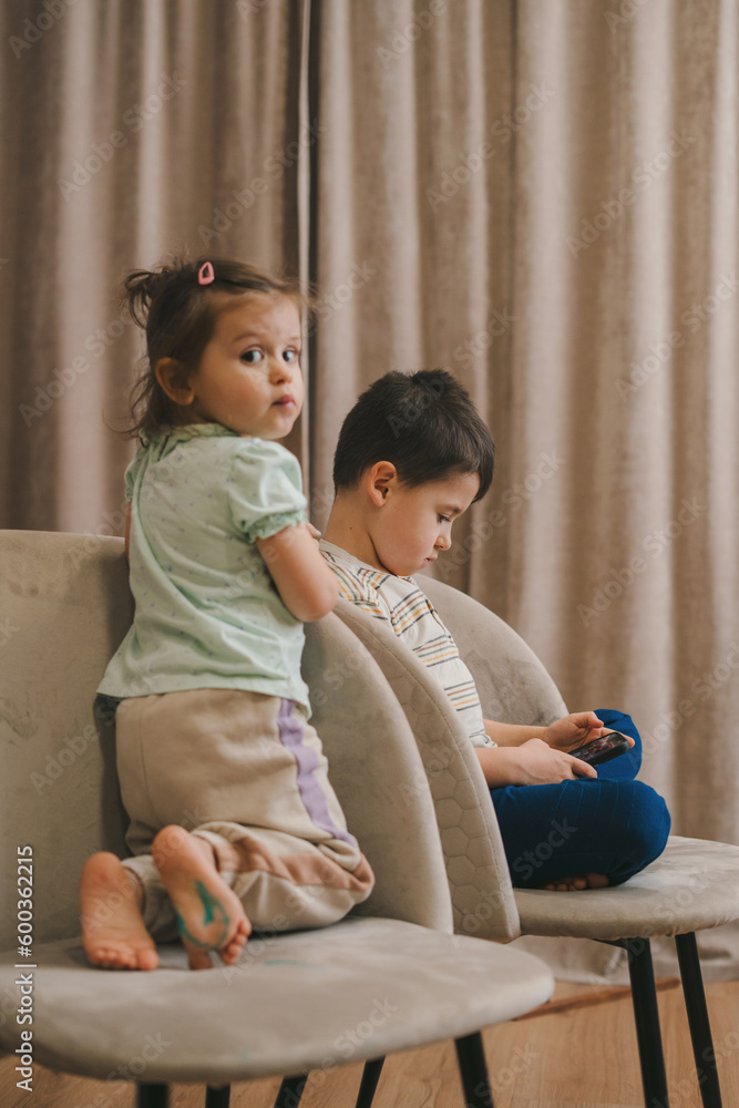 Baby girl sitting next to her brother who is playing games on the ...