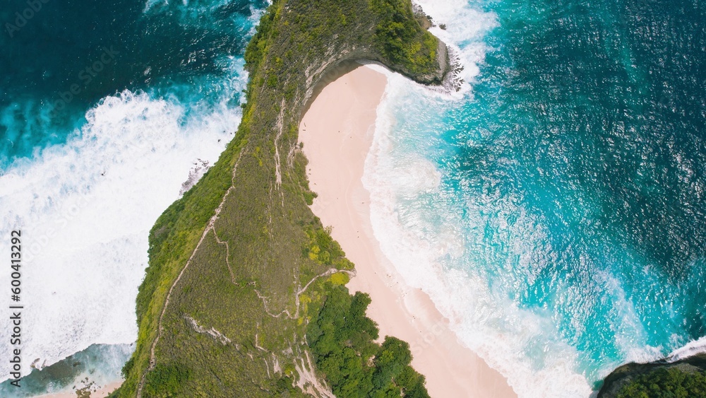 Kelingking sandy beach with tall overgrown rocky cliff and turquoise ...