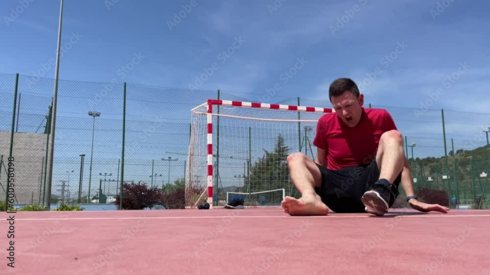 Twisted ankle. Futsal injury. Male falls down and touches foot in pain ...