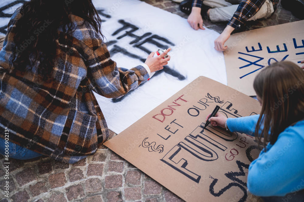 Group of teenagers multiracial girls draw signs with eco-themed slogans ...
