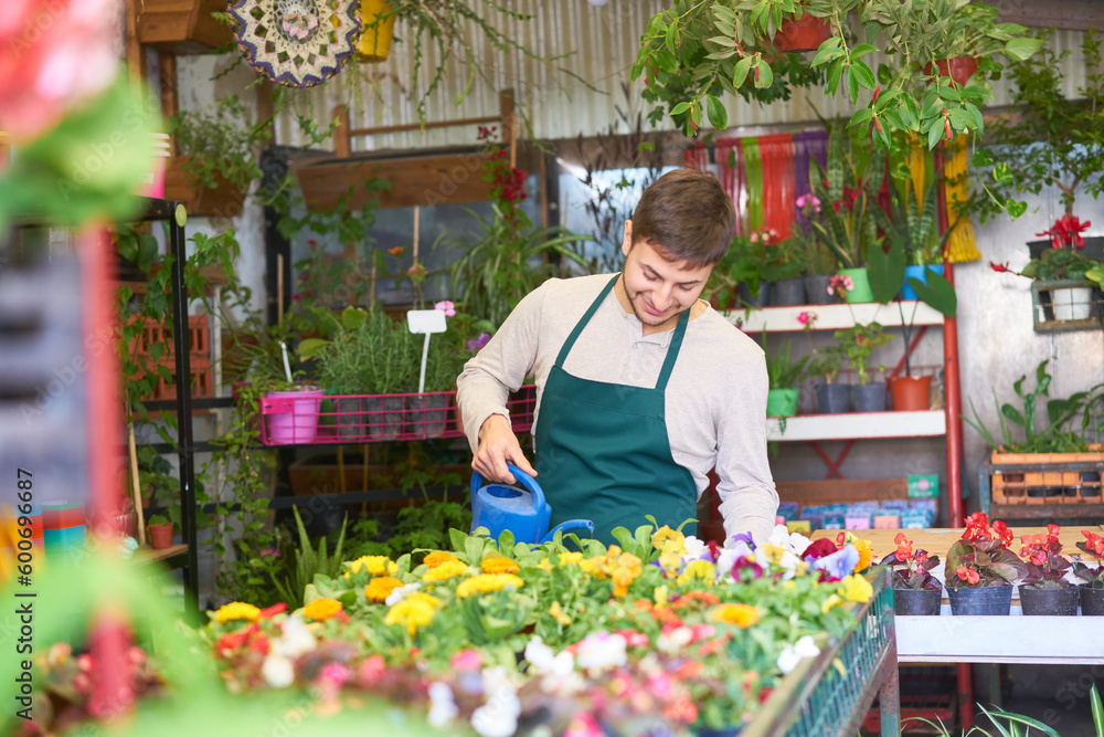 Young man as a gardener apprentice watering the flowers Stock Photo ...