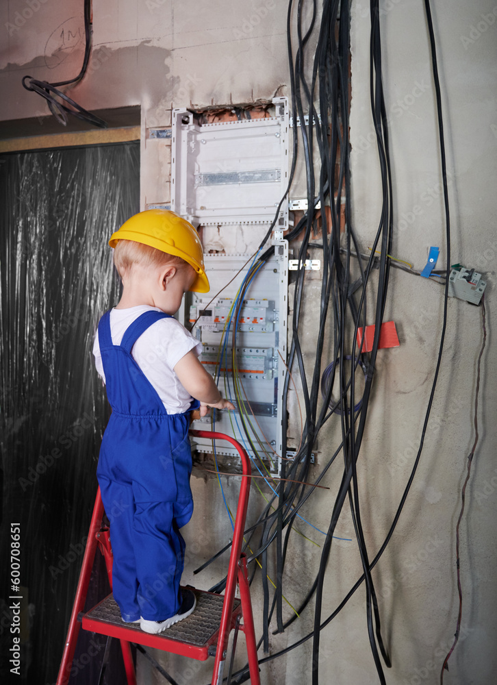 Back view of child electrician standing on ladder near electrical ...