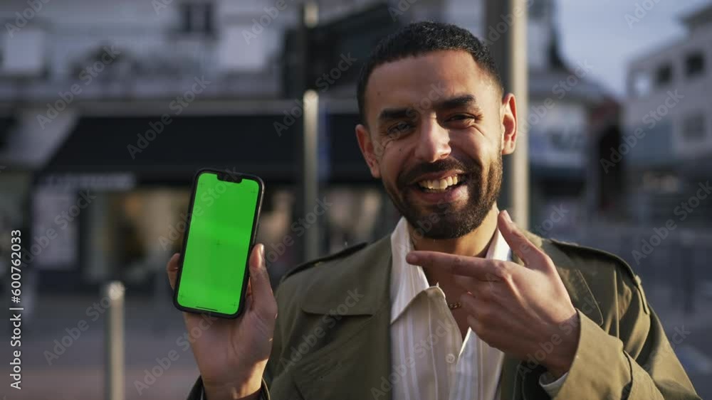 Portrait of a happy man showing cellphone to camera with chroma key ...