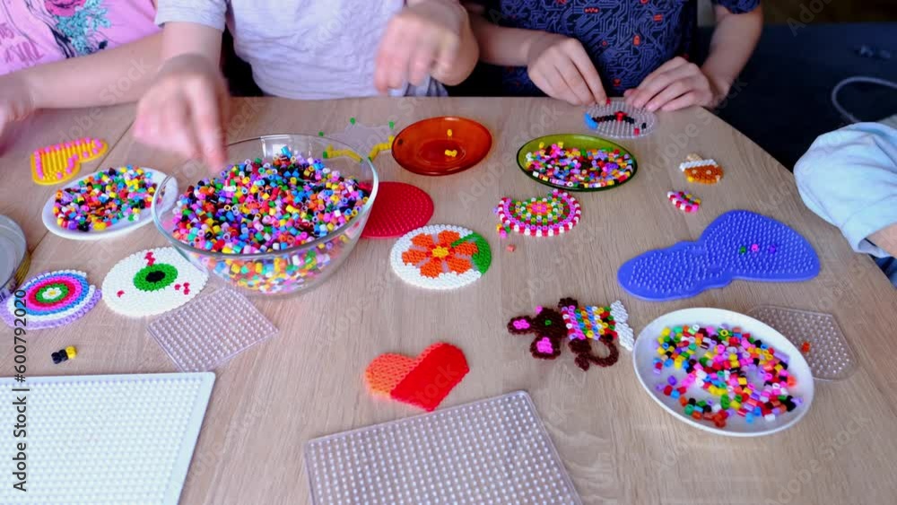 close-up of children's hands creating perler bead patterns, make crafts ...