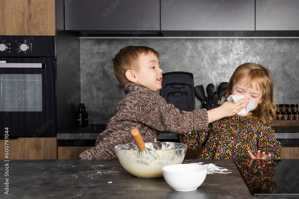 Little siblings cooking together on a modern kitchen, helping each ...