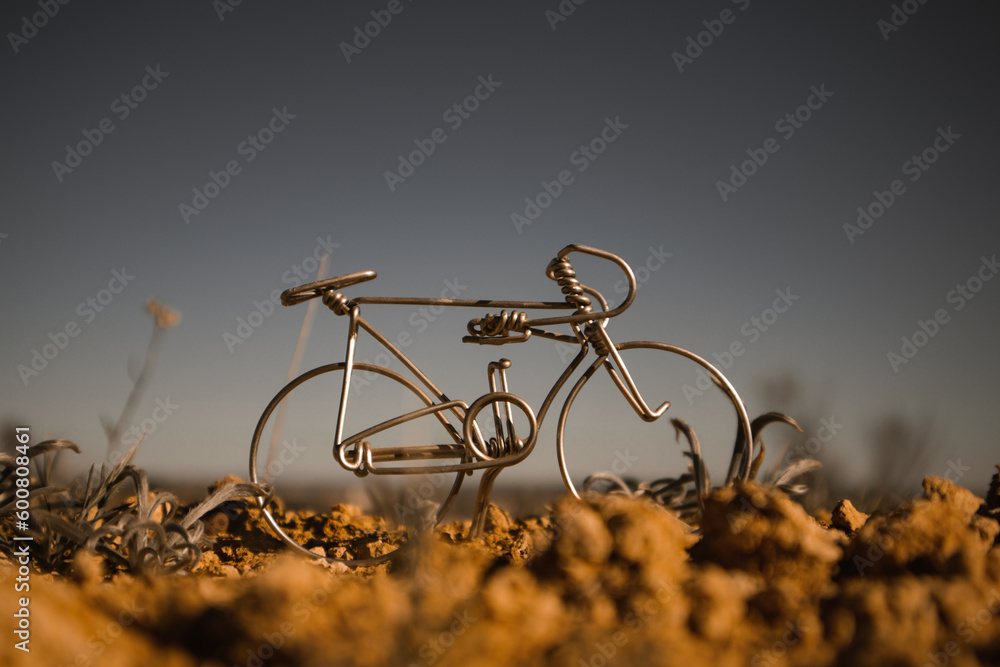 A miniature metal bicycle against a dark grey blue sky. Toy fake ...